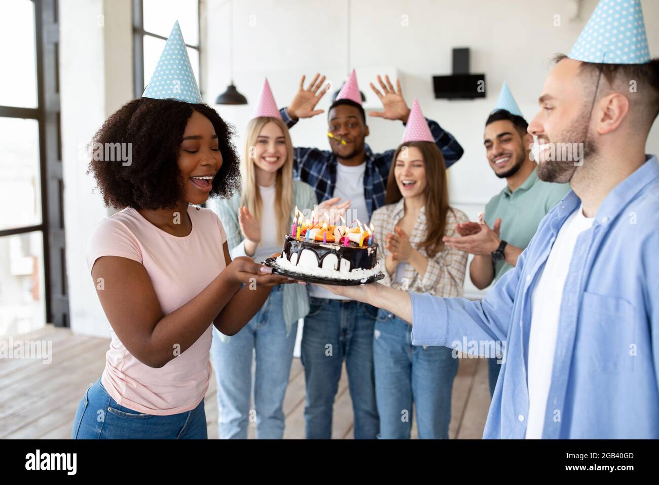 Group of cool multiethnic millennials celebrating birthday, presenting ...