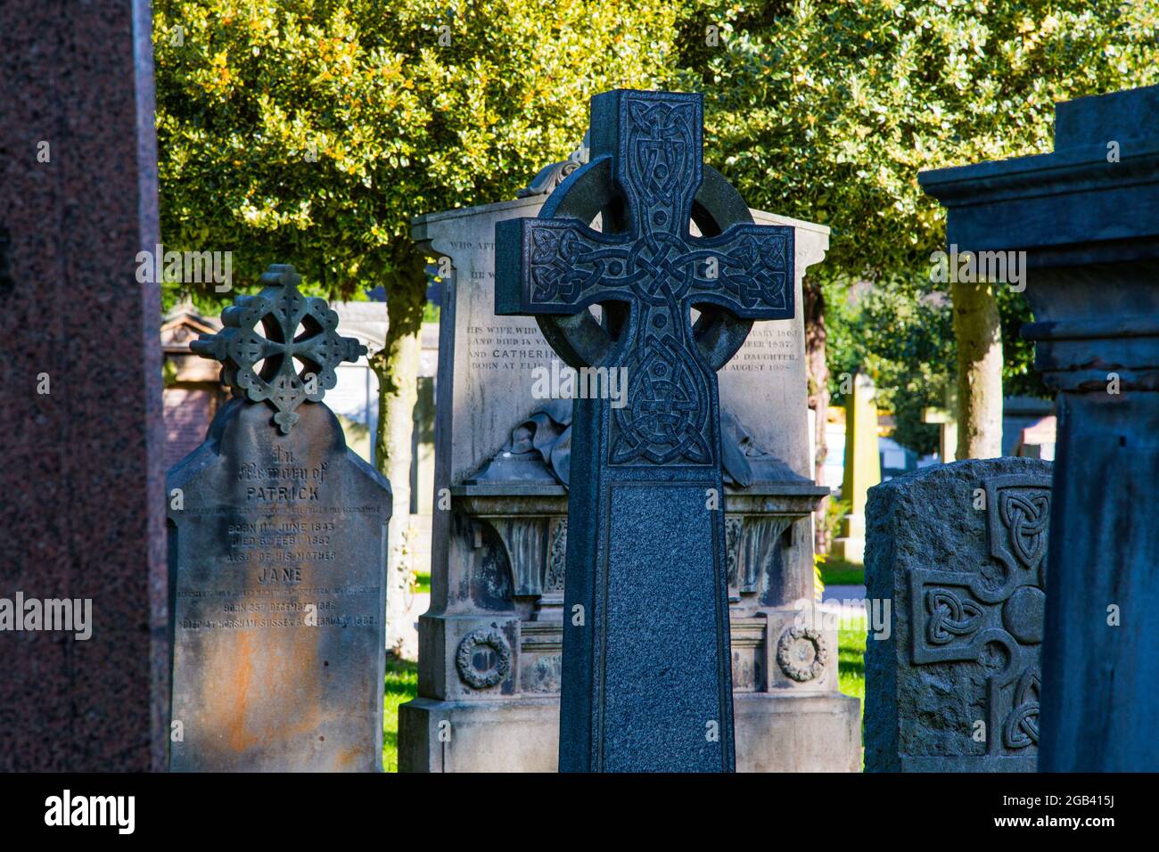 Gothic cemetery with graves in the ground and headstones in the shape ...