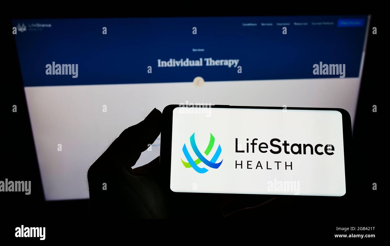 Person holding mobile phone with logo of American health care company ...