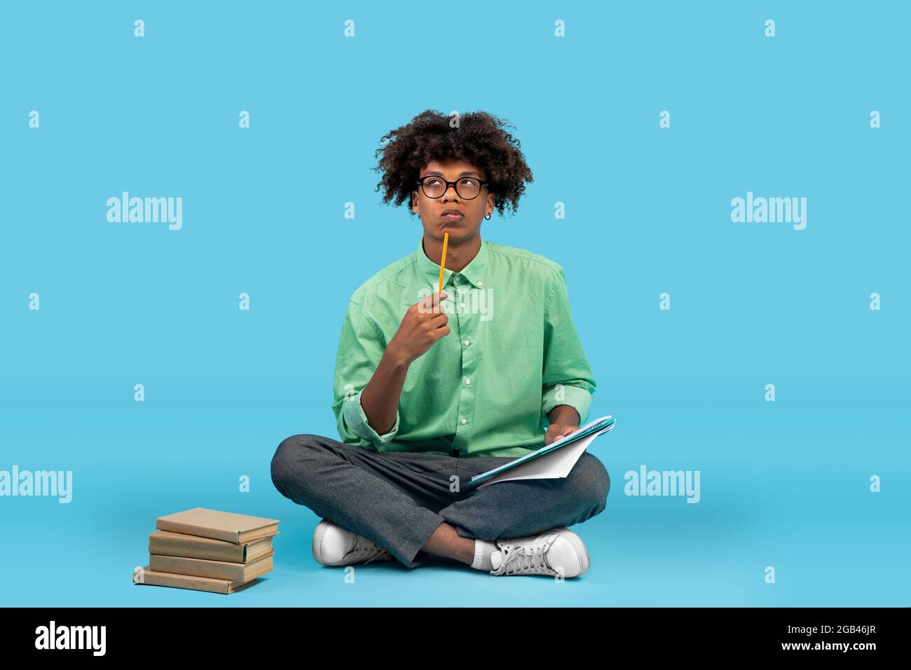 Thoughtful black guy student in glasses taking notes, holding notepad ...