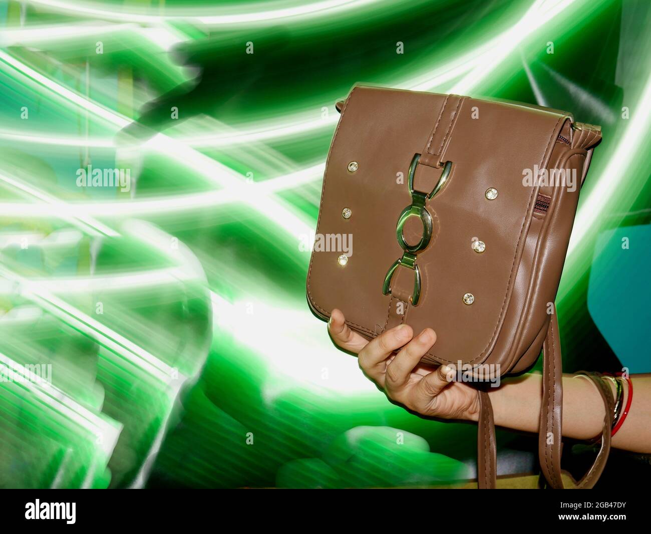 Woman bag presented on girl hand with light effect shine backdrop ...