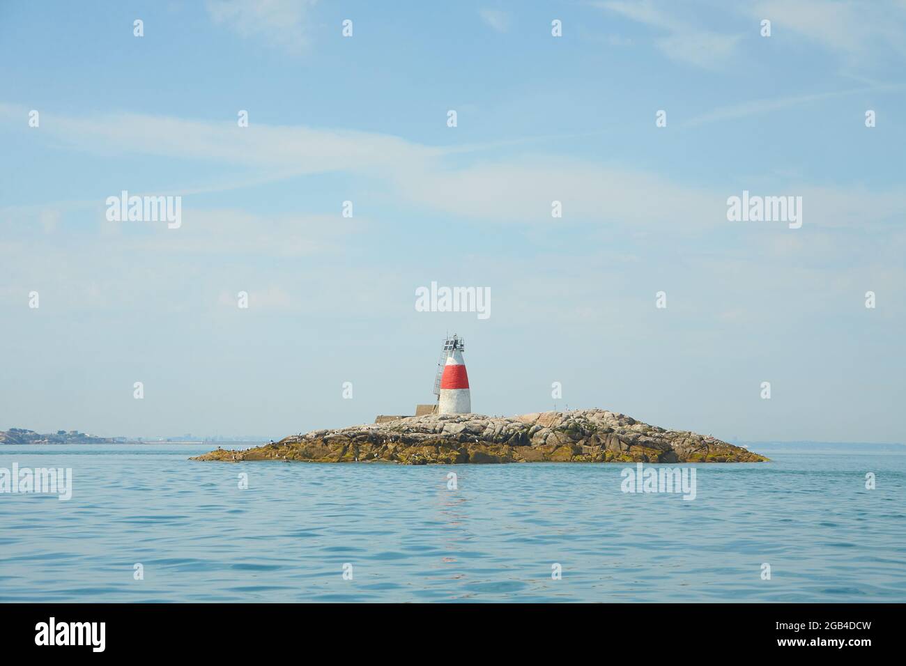 Old Muglins Lighthouse on the isolated island the backdrop of the blue ...