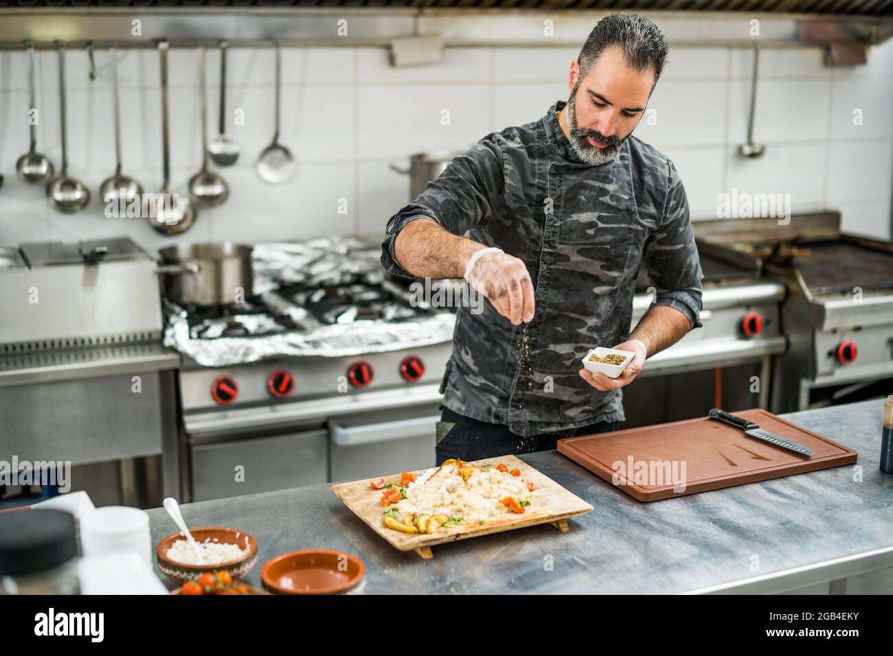 Professional cook is preparing meal in restaurant's kitchen. He is ...