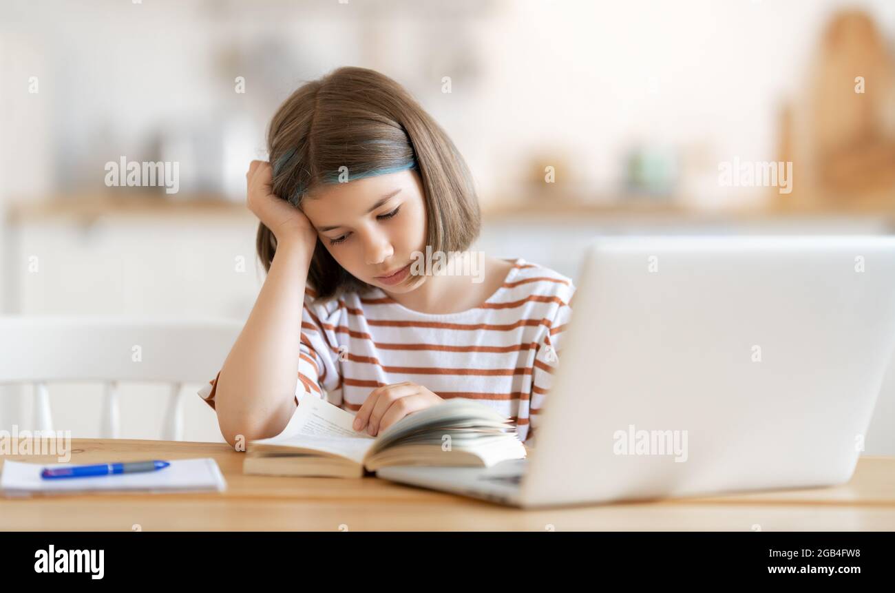 Back to school. Unhappy child is sitting at desk. Girl doing homework ...