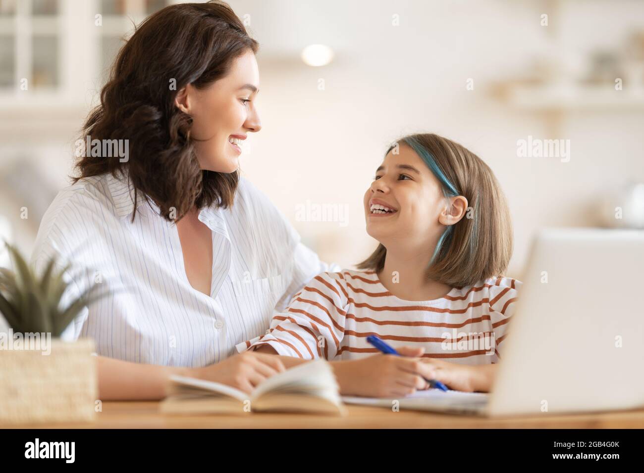 Back to school. Happy child and adult are sitting at desk. Girl doing ...