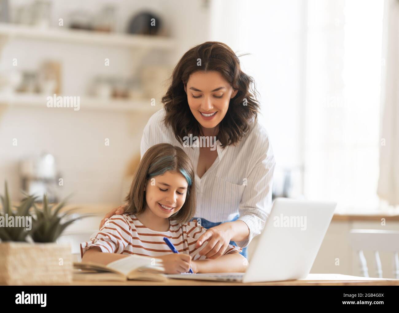 Back to school. Happy child and adult are sitting at desk. Girl doing ...