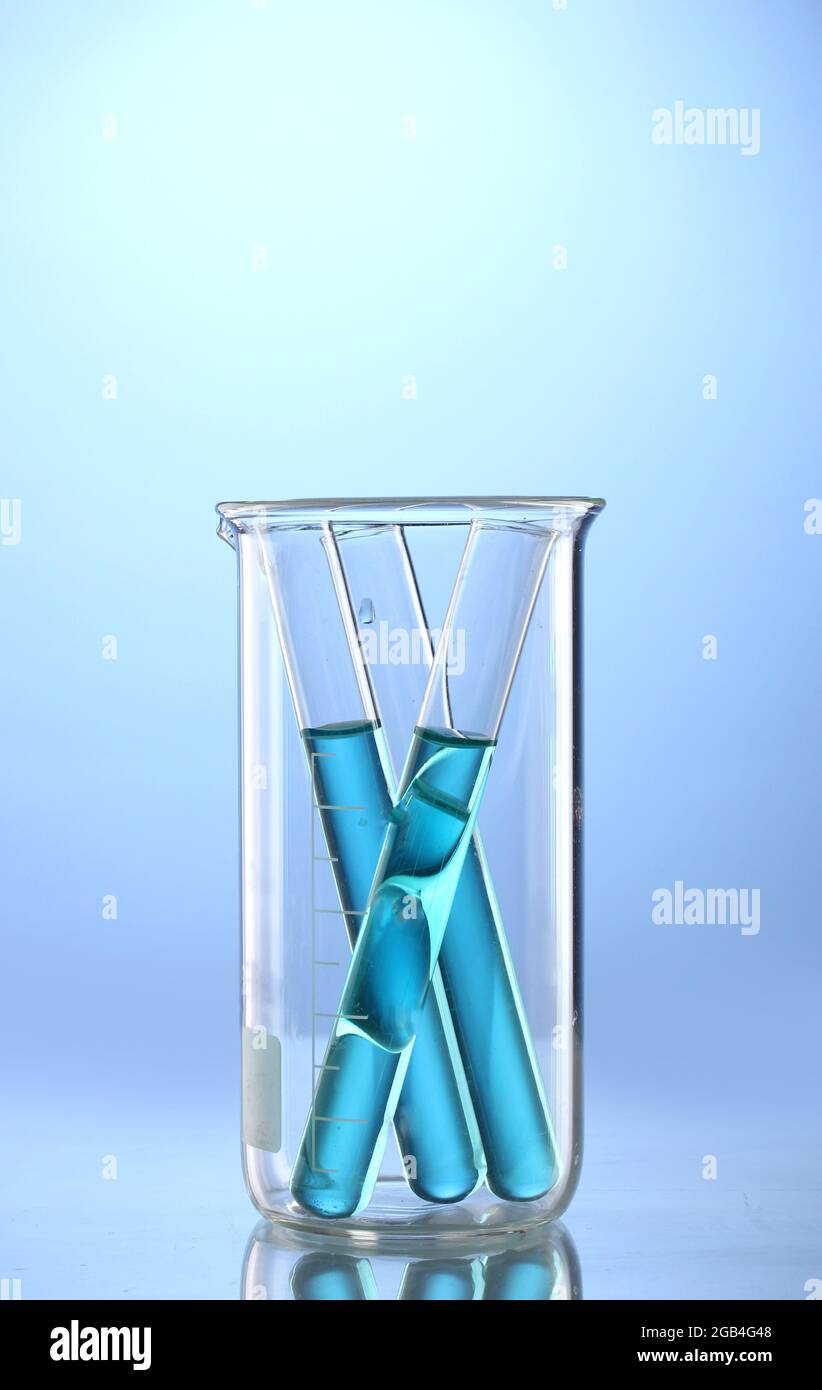 Laboratory tubes with blue liquid in measuring beaker with reflection ...