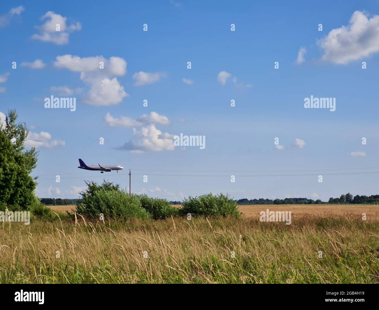 the plane is landing over a rural field on a sunny day Stock Photo - Alamy