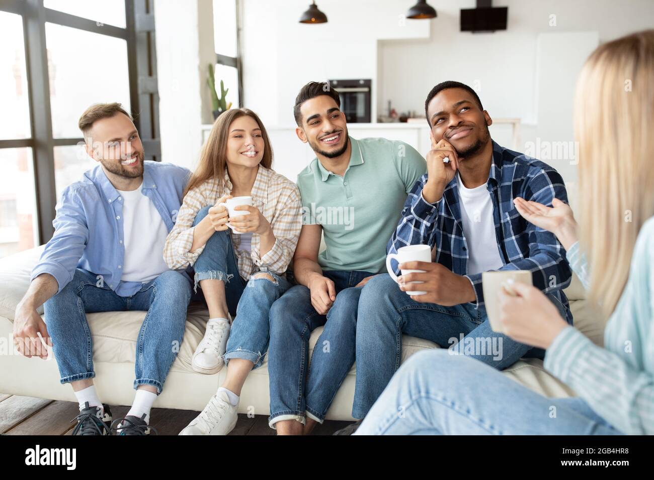 Multiethnic young friends enjoying conversation, drinking tea or coffee ...