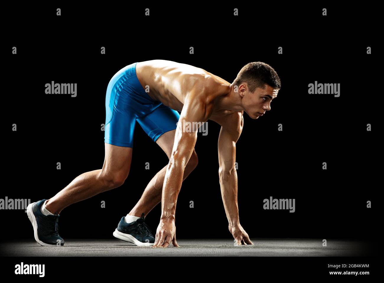 Side view of young professional male athlete, runner preparing to start ...