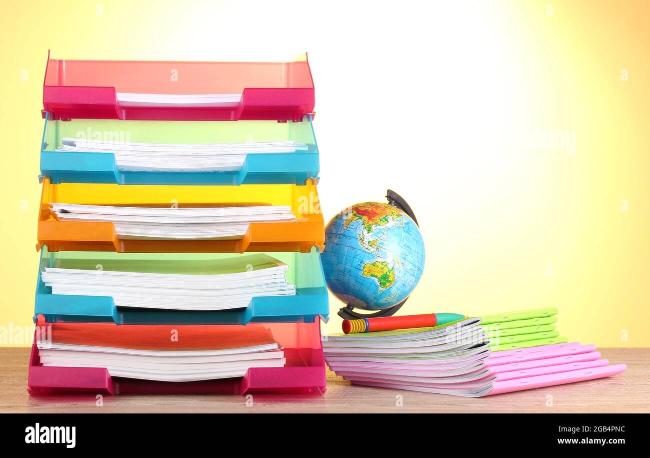 bright paper trays and stationery on wooden table on yellow background ...