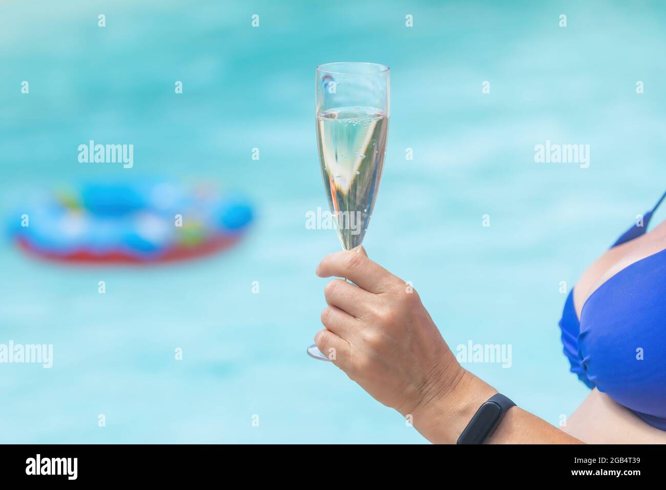 Female model is holding glass of champagne in the pool. Bathing ring is ...