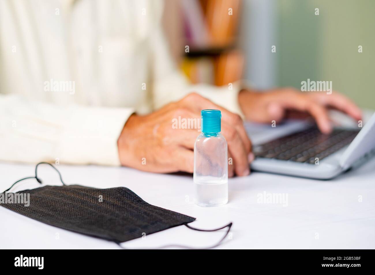 Focus on sanitizer, Unrecognizable man working on laptop at home while ...