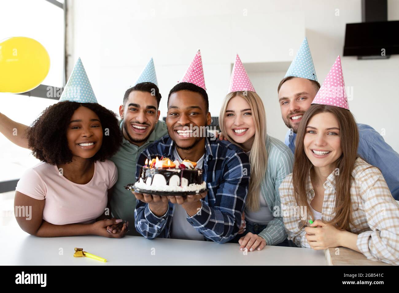 Portrait of happy multiethnic friends wearing party hats, posing with ...