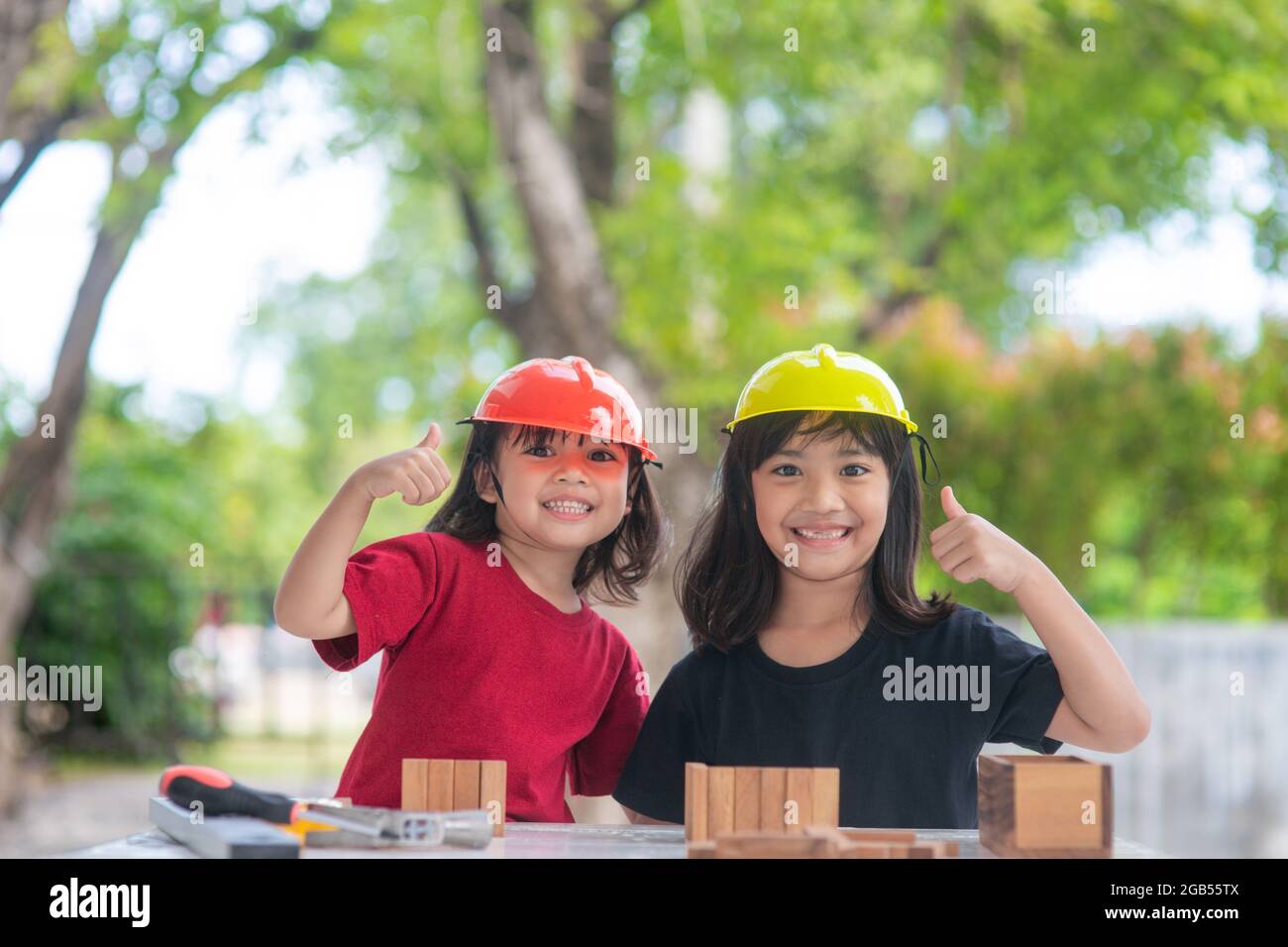 Asian Siblings girls wearing engineering hats building House from the ...
