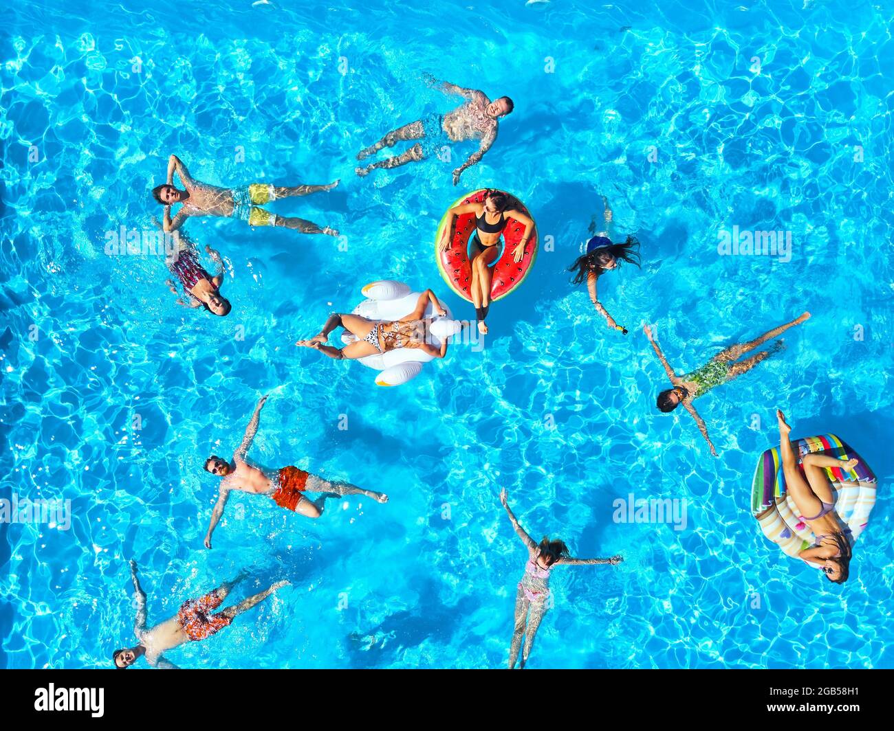 Aerial of friends having party in swimming pool with inflatable ...