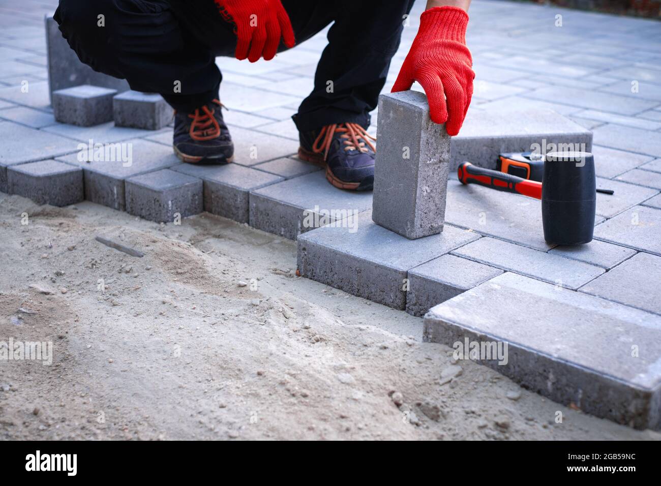 The master in yellow gloves lays paving stones in layers. Garden brick ...