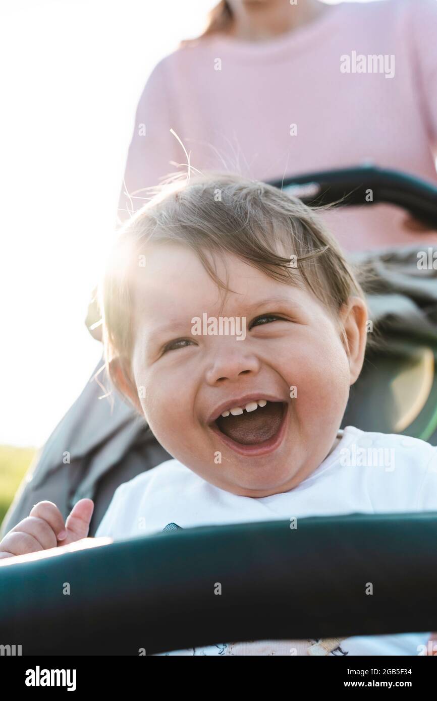 Happy laughing baby girl enjoying a walk in a park sitting in the ...
