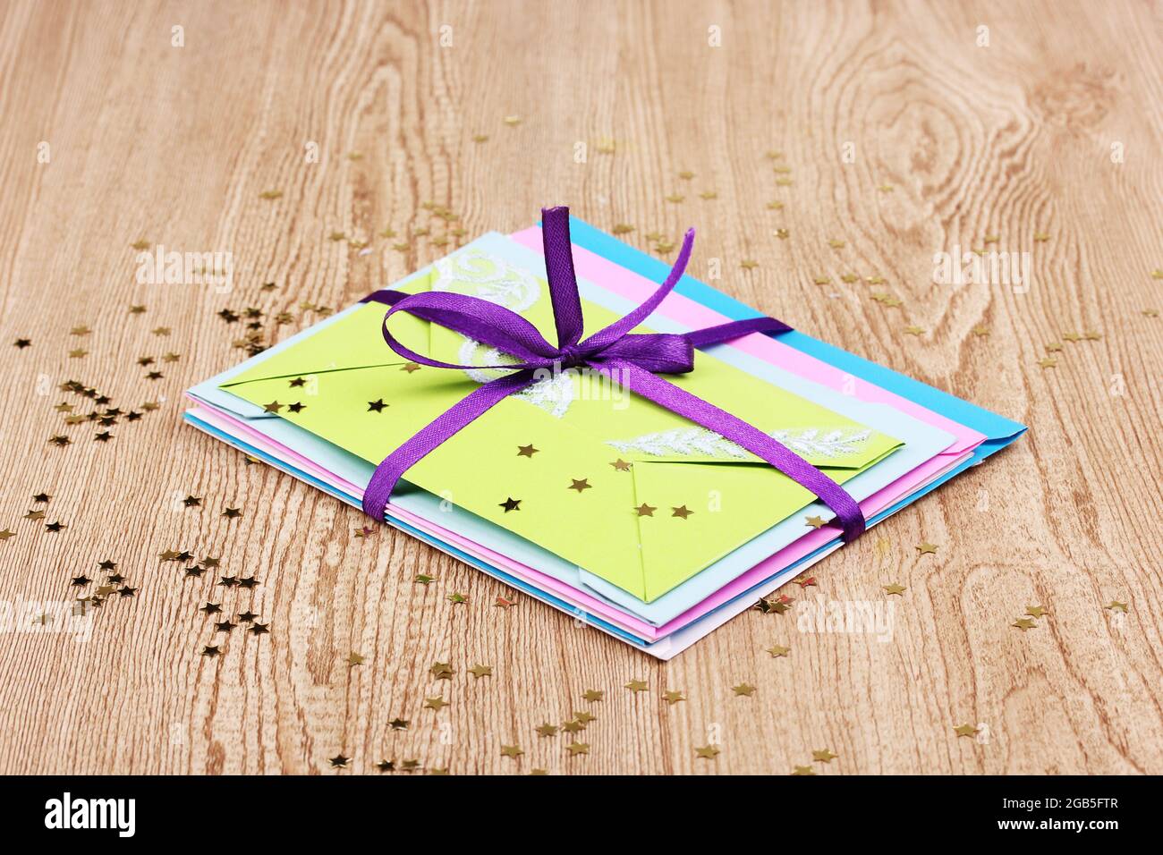 Bunch of color envelopes with ribbon and confetti on wooden background ...