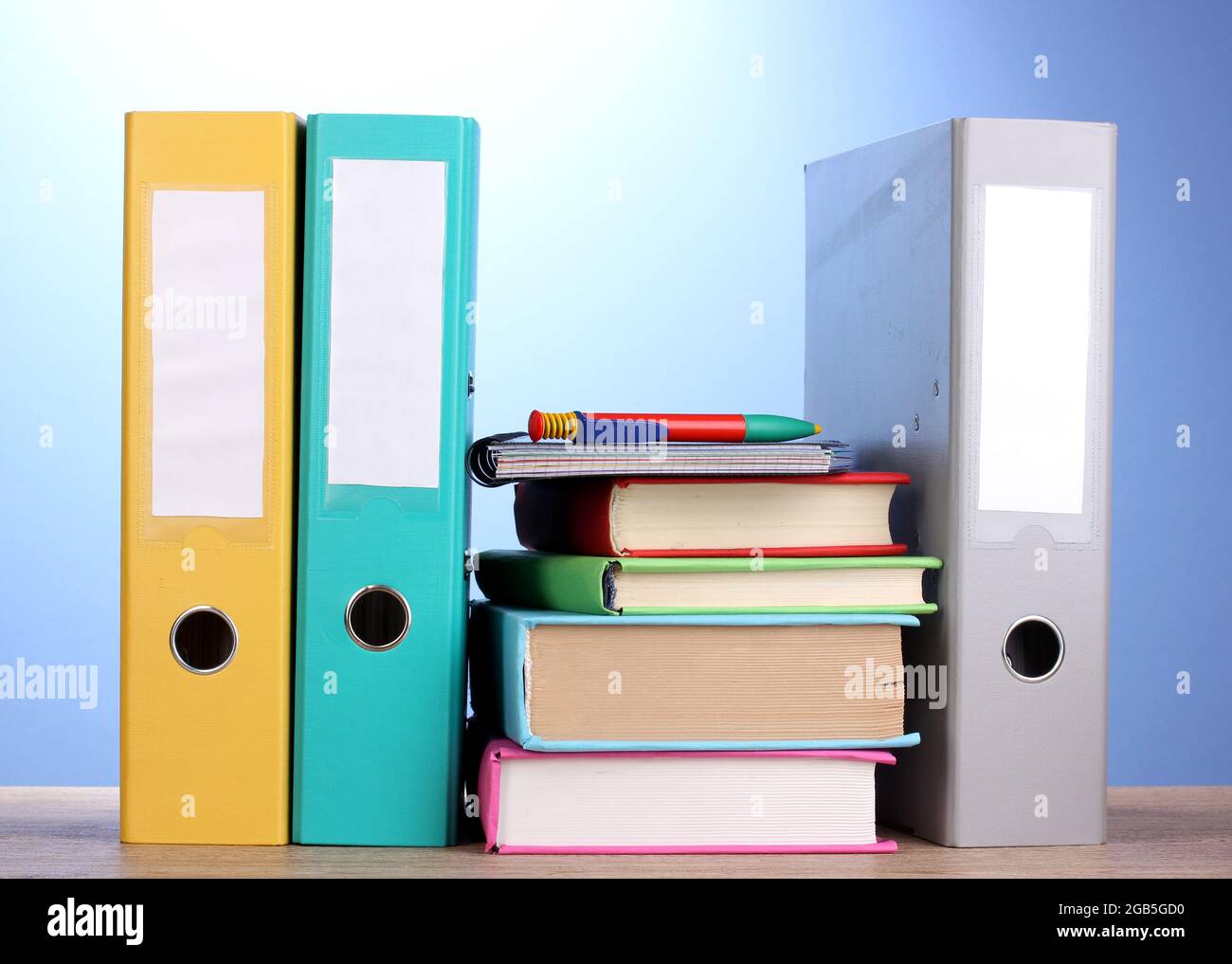 Bright office folders and books with stationery on wooden table on blue ...