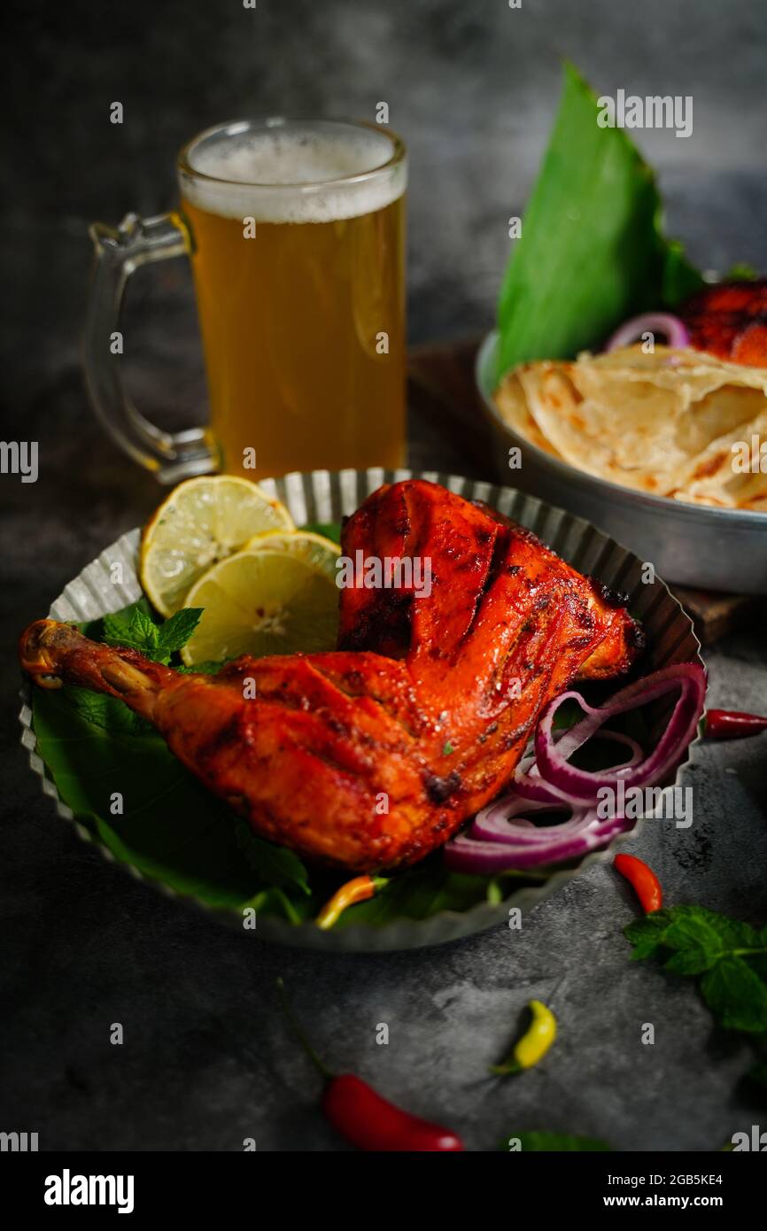 Homemade Tandoori chicken leg pieces served in a plate with roti ...