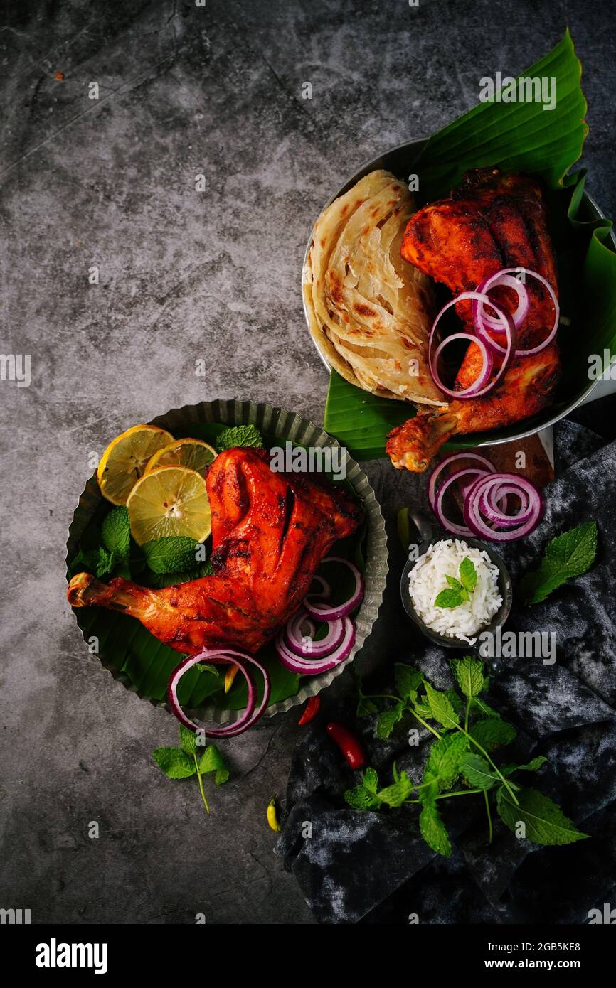 Homemade Tandoori chicken leg pieces served in a plate with roti ...