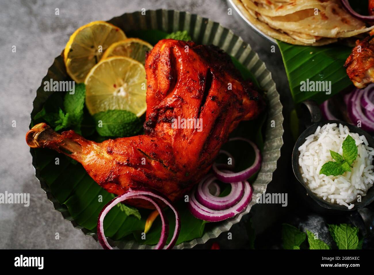 Homemade Tandoori chicken leg pieces served in a plate with roti ...