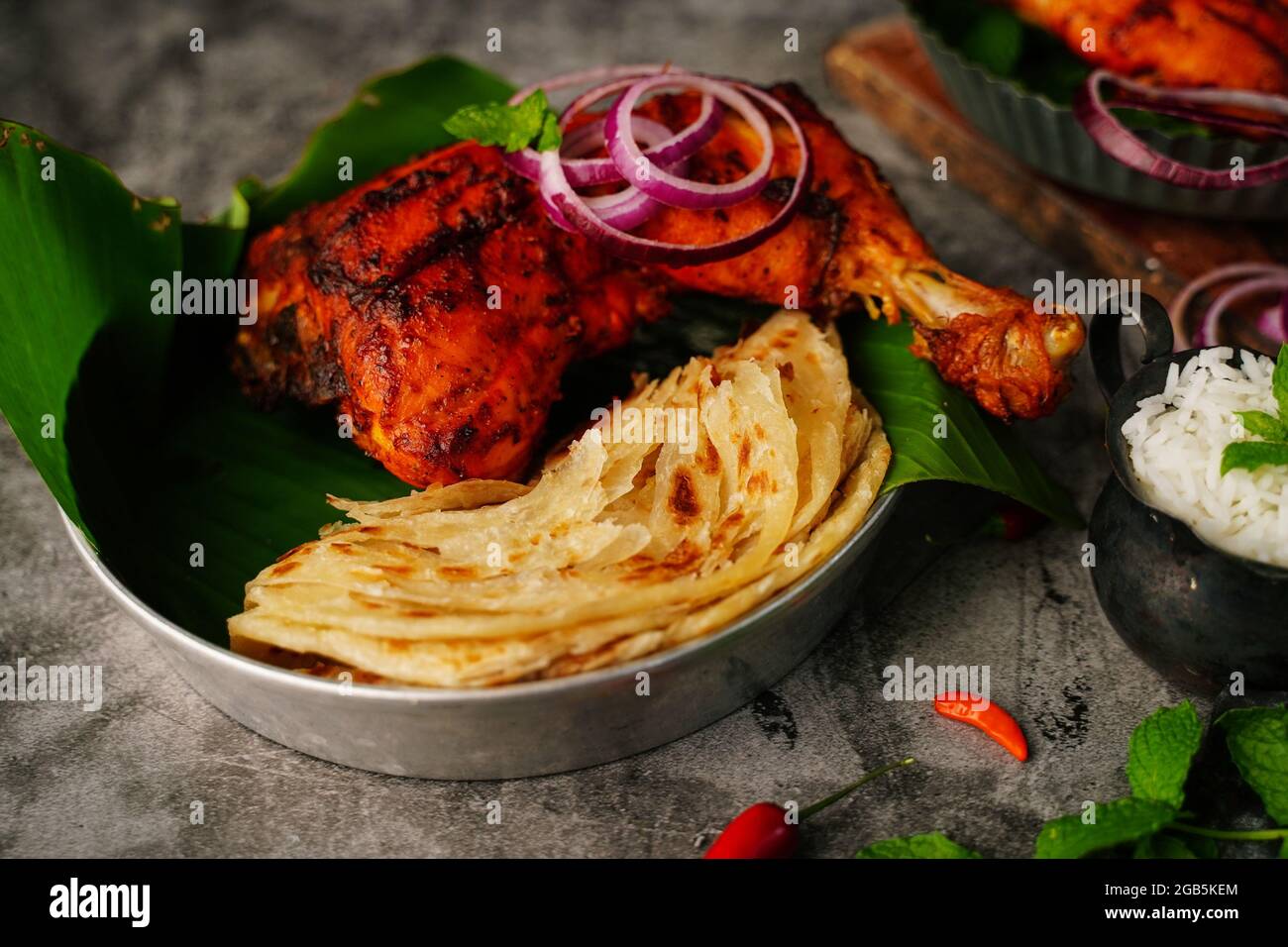 Homemade Tandoori chicken leg pieces served in a plate with roti ...