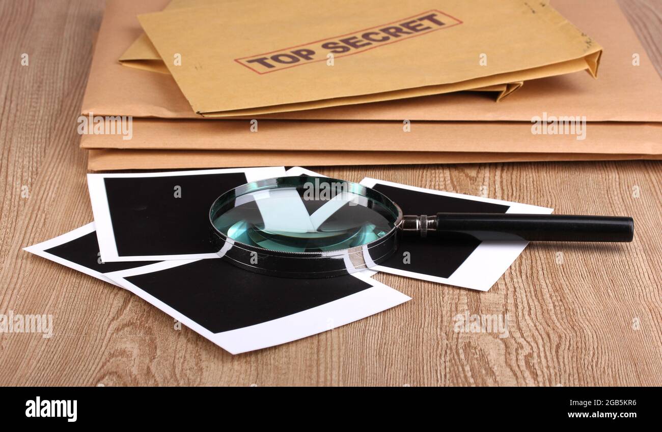 Envelopes with top secret stamp with photo papers and magnifying glass ...