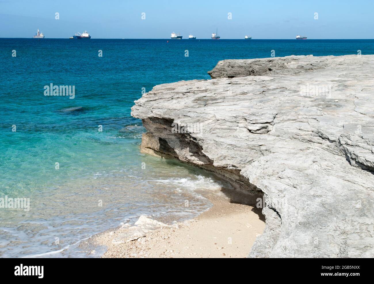 The eroded rocky Grand Bahama island coastline and cargo ships in a ...