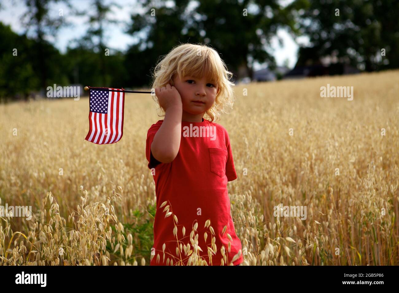 Handsome fair-haired baby boy with a red t-shirt holding an American ...
