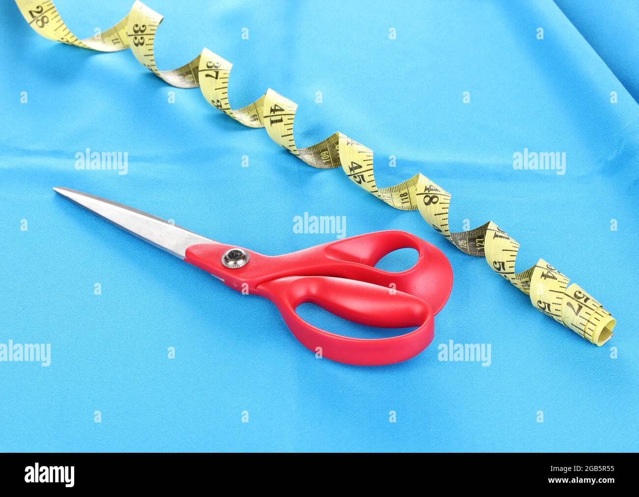 Scissors and measuring tape on blue fabric Stock Photo - Alamy