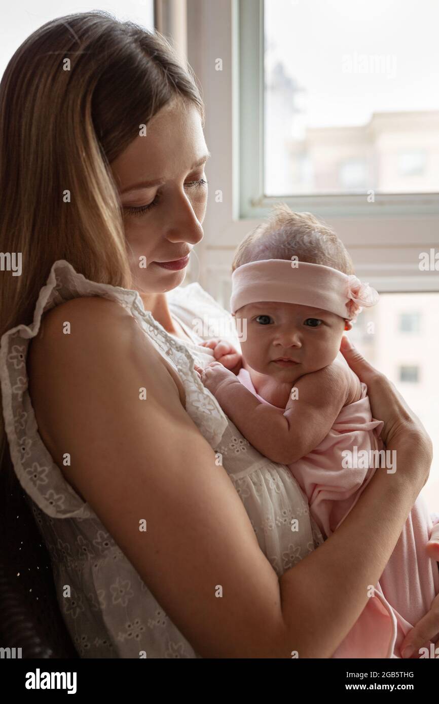Portrait of young Caucasian mother holds hug little newborn baby two ...