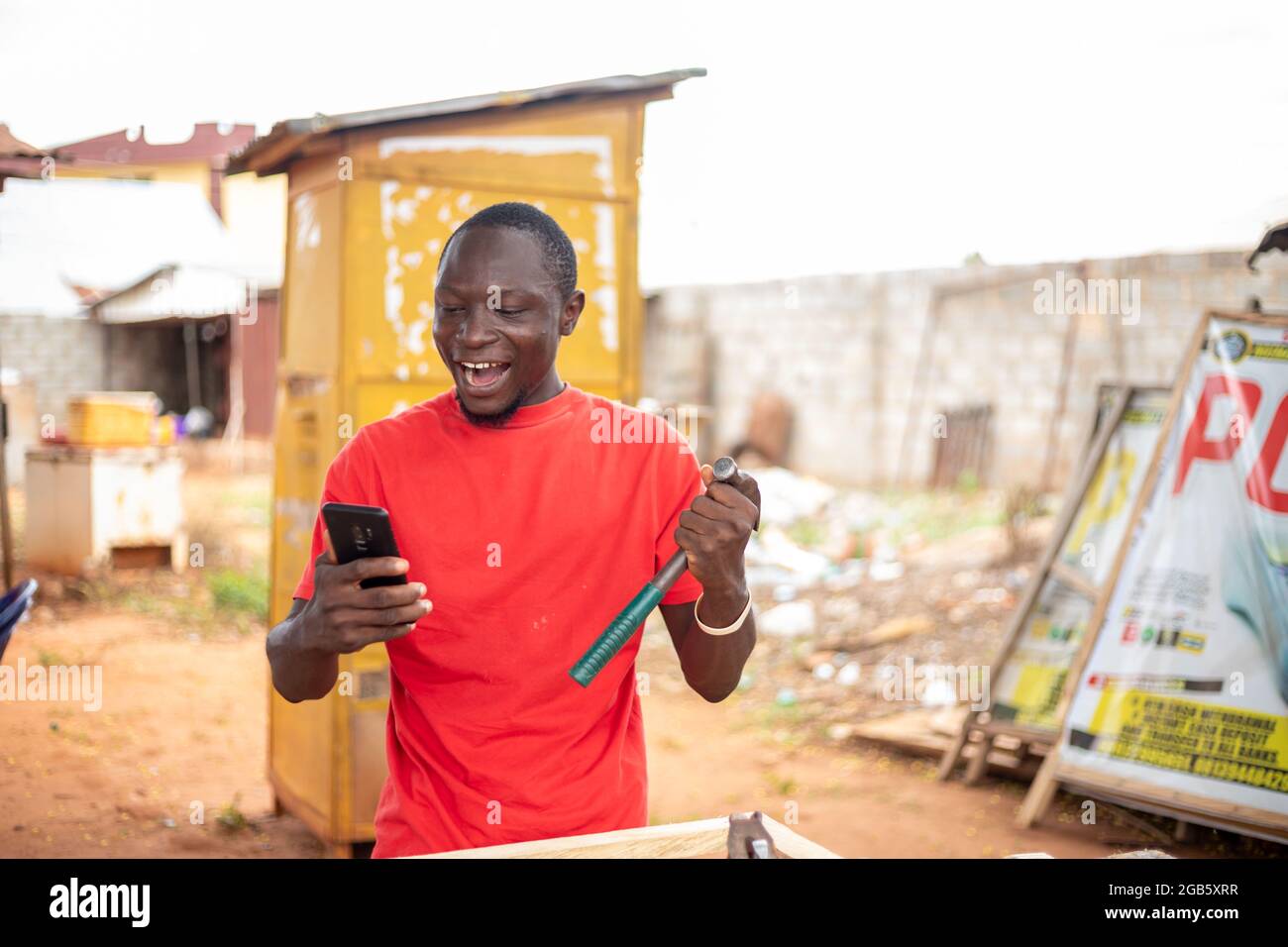 Man holding a metal hammer and looking at his phone at the construction ...
