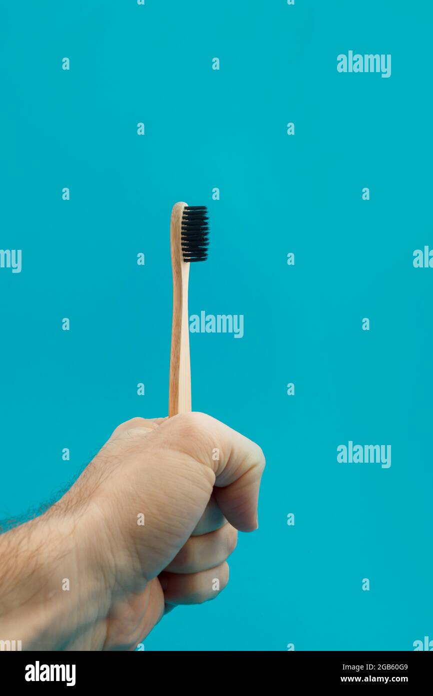 Wooden toothbrush in hand on blue background Stock Photo - Alamy