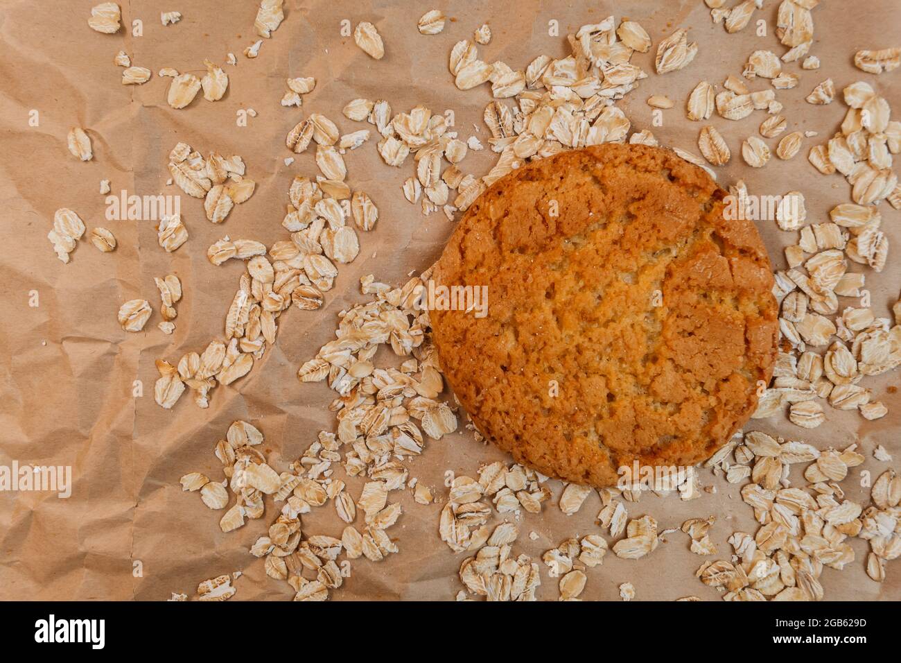 oatmeal cookies and scattered oatmeal on crumpled paper background ...