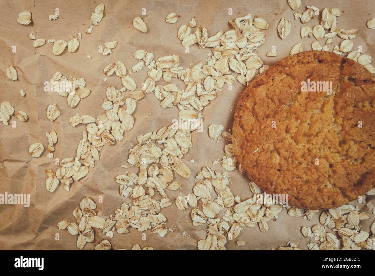 oatmeal cookies and scattered oatmeal on crumpled paper background ...