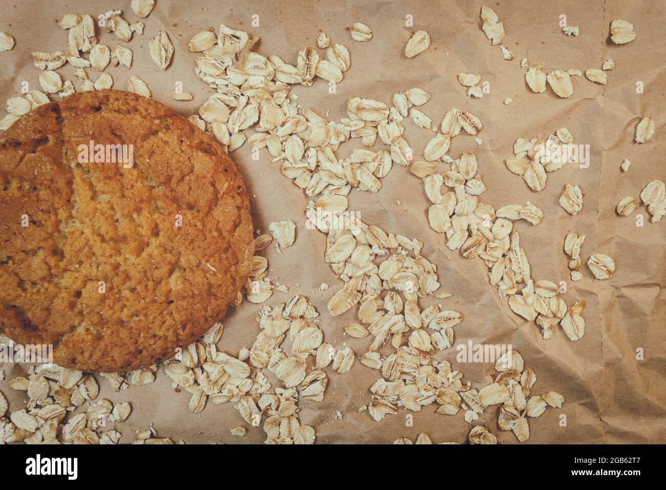 oatmeal cookies and scattered oatmeal on crumpled paper background ...