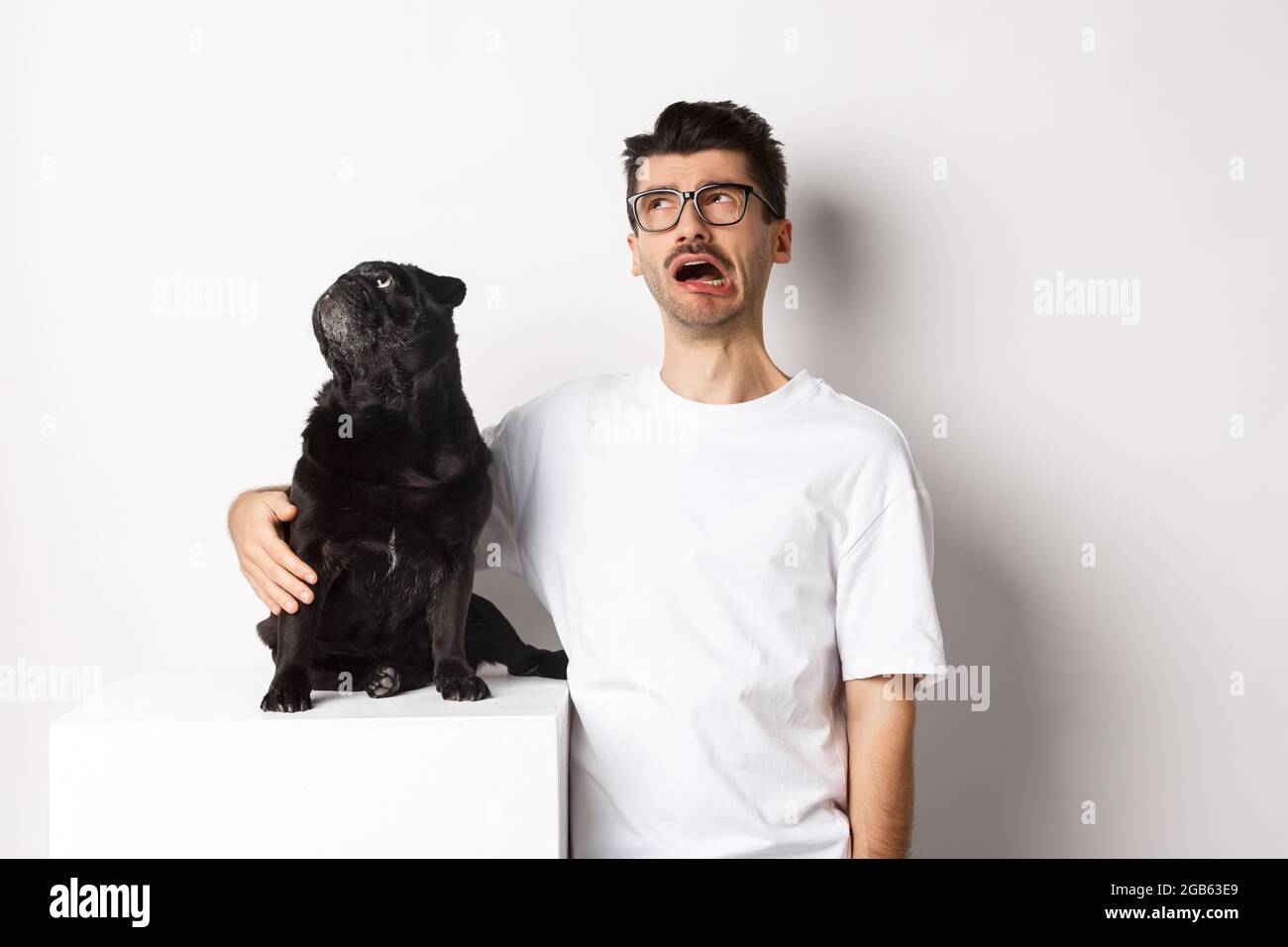 Whining man looking sad while pug staring intrigued at upper left ...