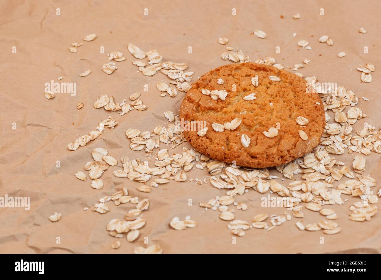 oatmeal cookies and scattered oatmeal on crumpled paper background ...
