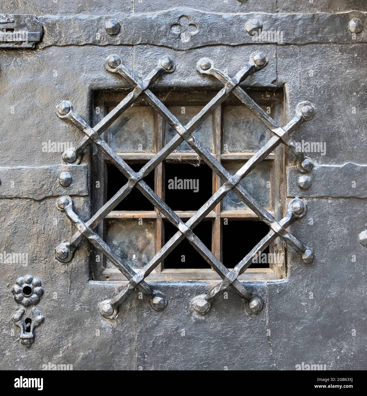 Old window behind metal grate in medieval door Stock Photo - Alamy