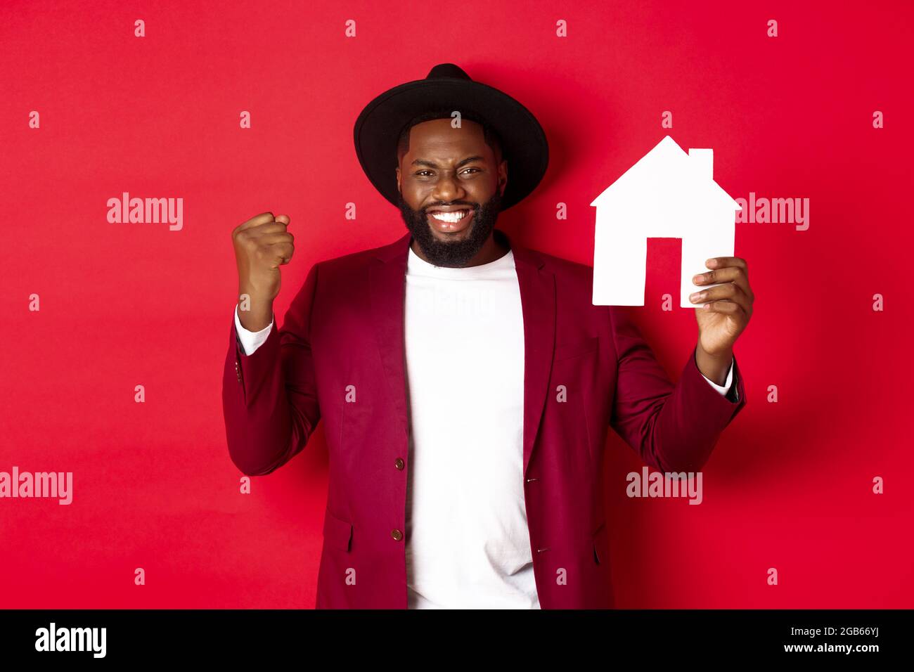 Real estate. Cheerful Black man rejoicing and showing paper home maket ...