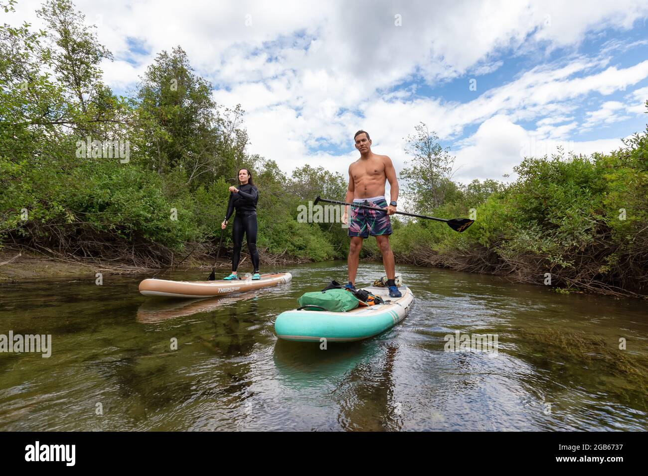 Adventurous people paddle boarding in a river Stock Photo - Alamy