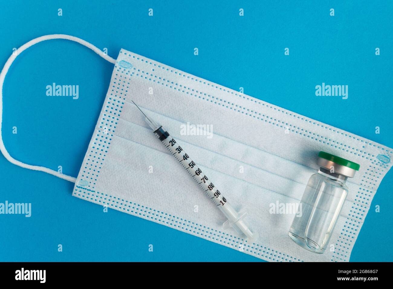syringe, medical mask and ampoule with medicine on a blue background ...