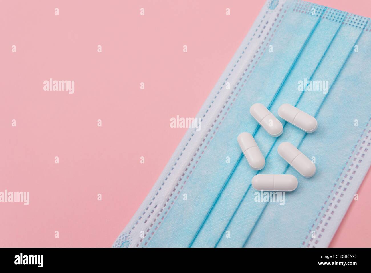White Pills or Tablets on Medical Face Mask, Lying on Pink Background ...