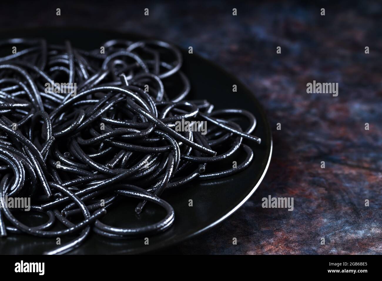 Black pasta on a black plate. Black spaghetti cuttlefish ink on a dark ...