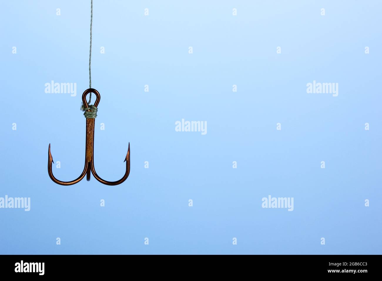 Treble fish hook on blue background Stock Photo - Alamy