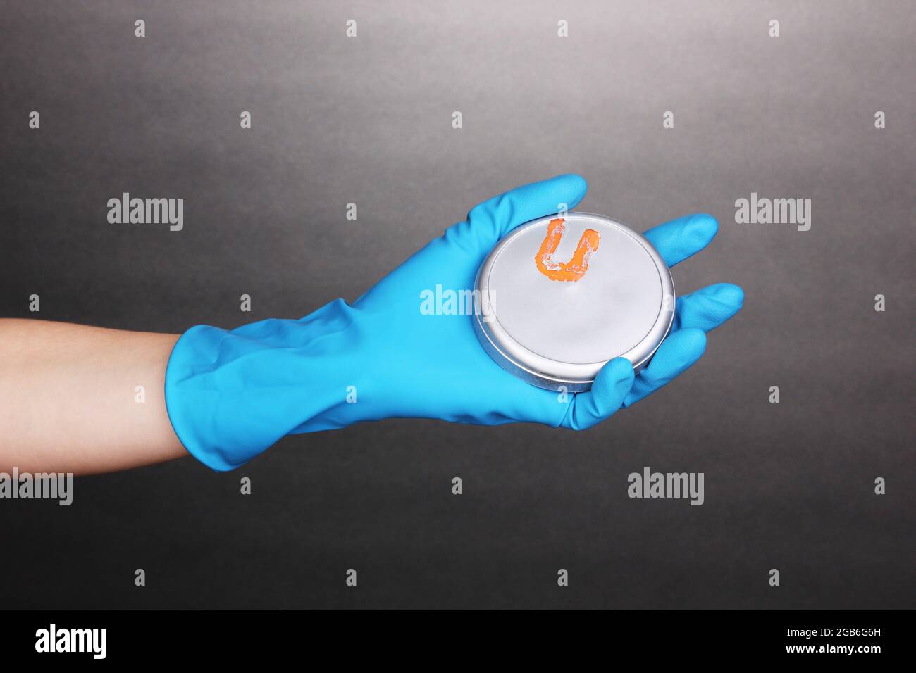 Uranium in hand on grey background Stock Photo - Alamy