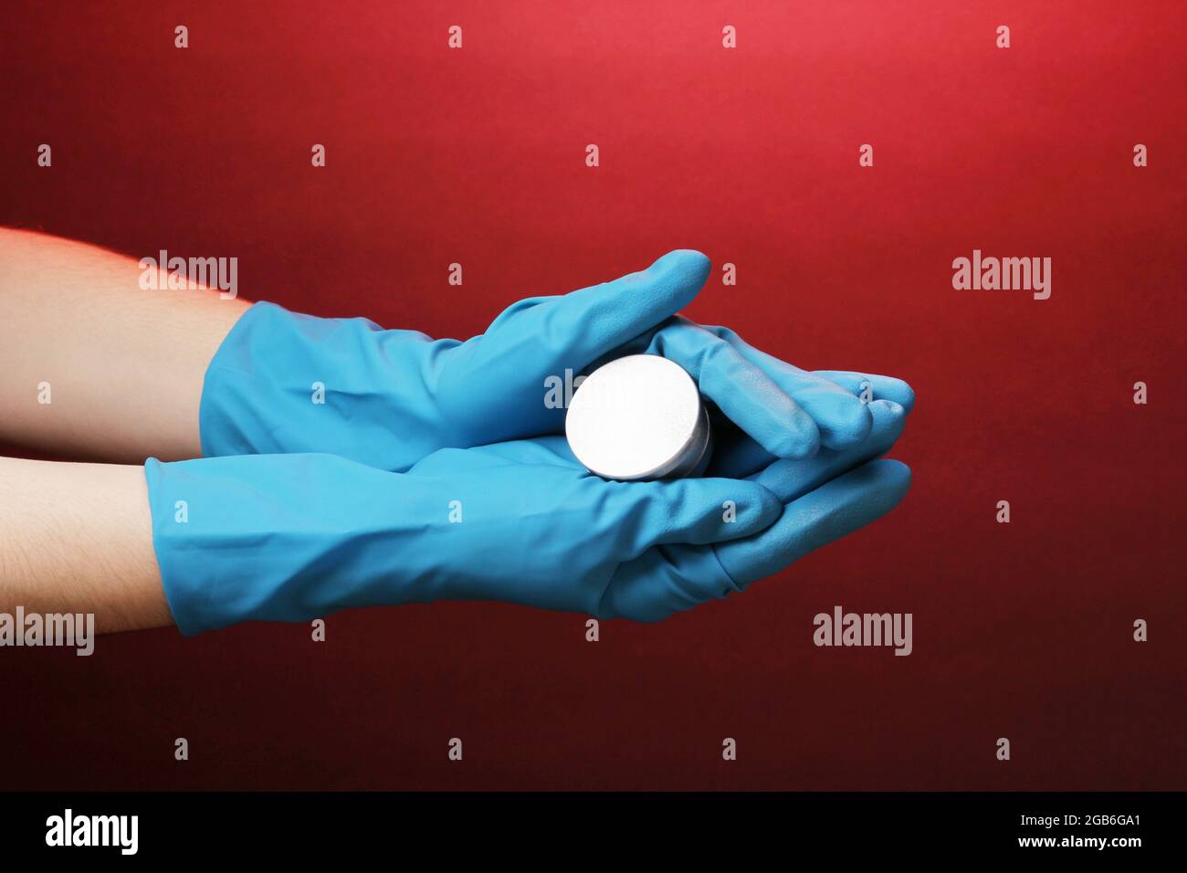 Uranium in hand on red background Stock Photo - Alamy