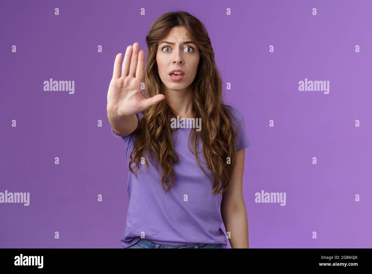 Worried shocked curly-haired woman gasping stare camera anxiously pull ...